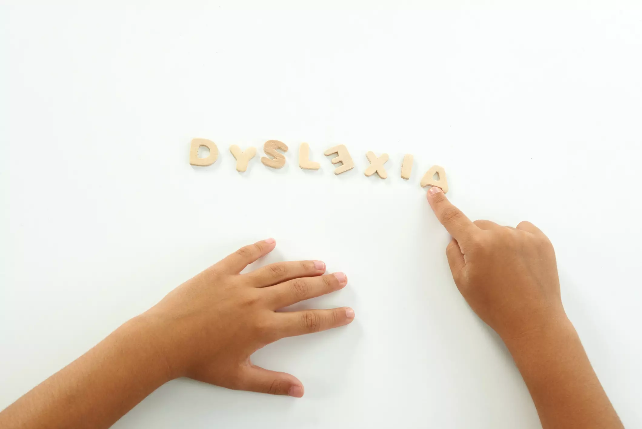 le mani di una ragazza formano la parola dislessia con lettere di legno