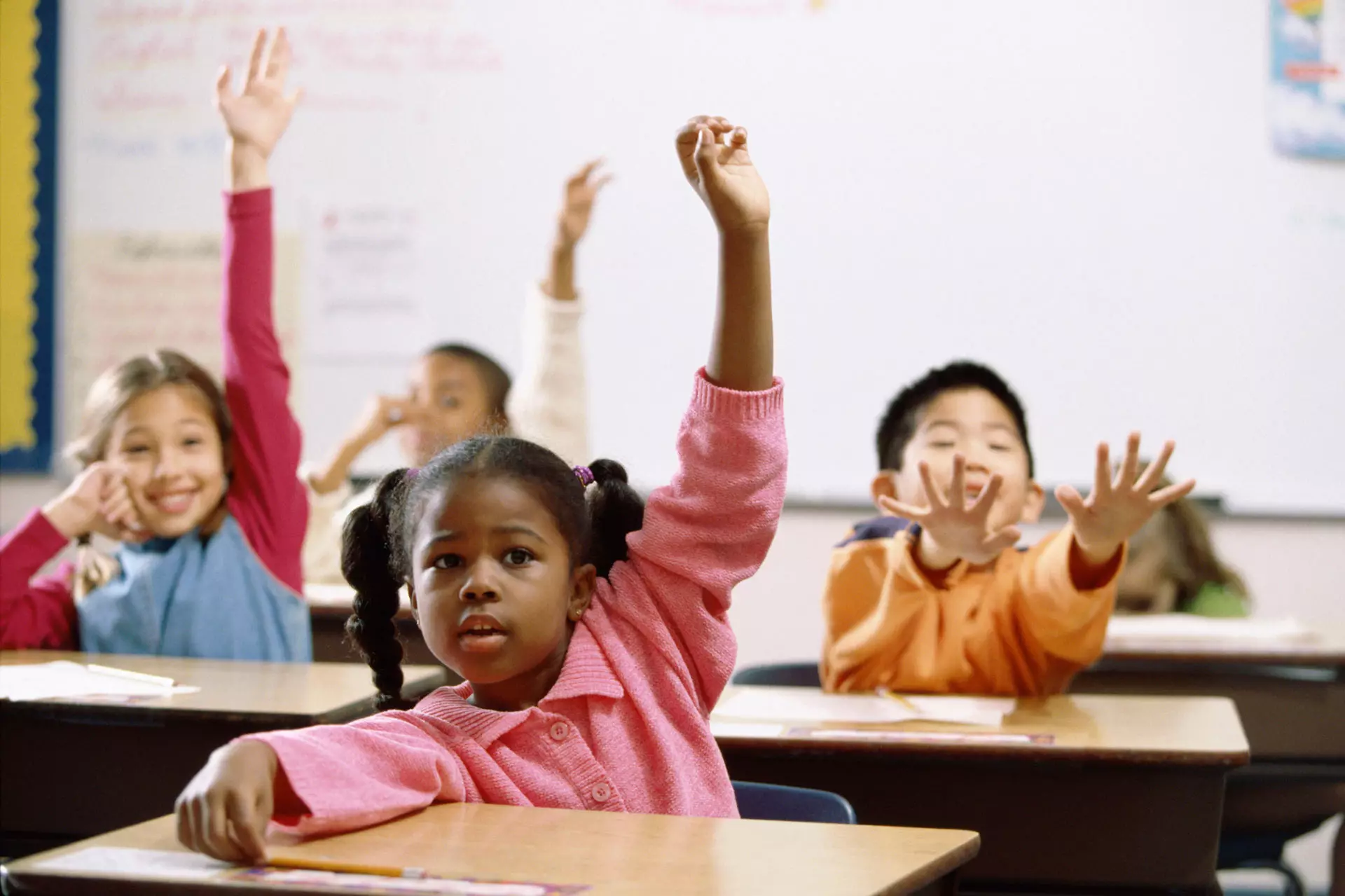 Gyerekek kézfelemeléssel az osztályteremben, a kérdés megválaszolásának szabályait betartva