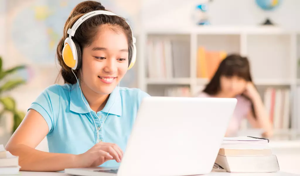 ADHD ունեցող երիտասարդ աղջիկ դպրոցում իր համակարգչի վրա աջակցող տեխնոլոգիա է օգտագործում