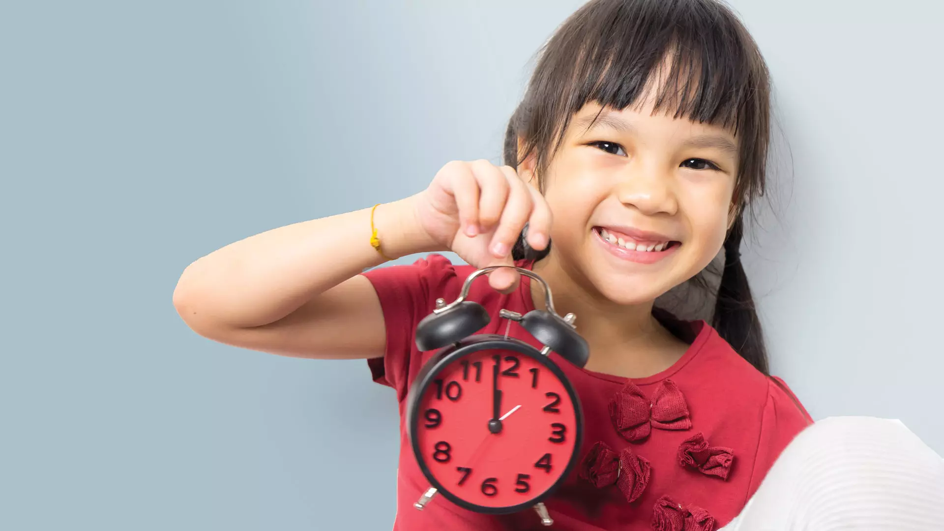 Une jeune fille atteinte de TDAH tenant une horloge, souriant après une pause qui a vraiment fonctionné