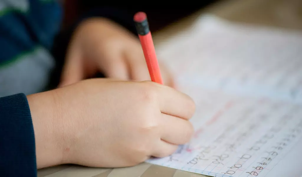 ADHD-s diák kezei, akik jegyzetfüzetben írnak és gyakorolják a tollbamondást