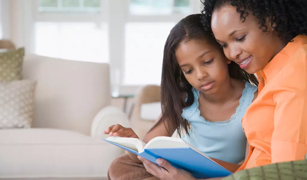 Mama pomaga hčerki z ADHD pri bralnem razumevanju v njihovi dnevni sobi