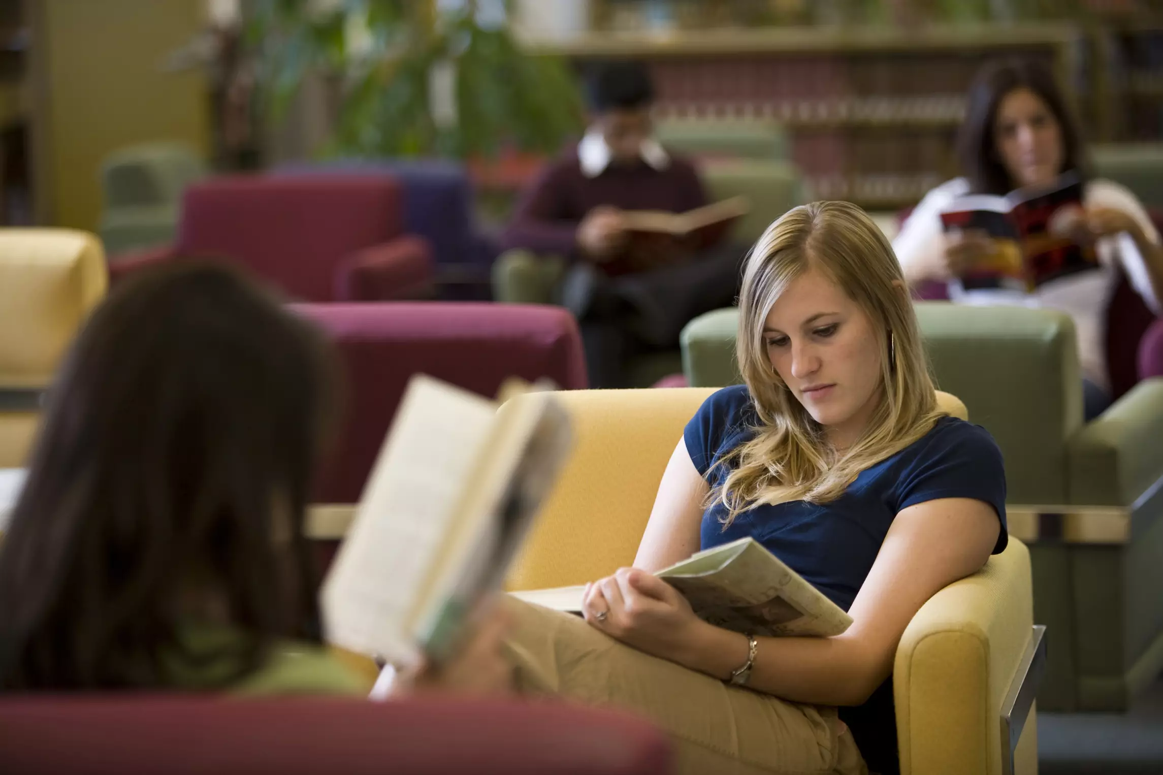 Студент с СДВГ читает в библиотеке, готовясь подать заявку на стипендию
