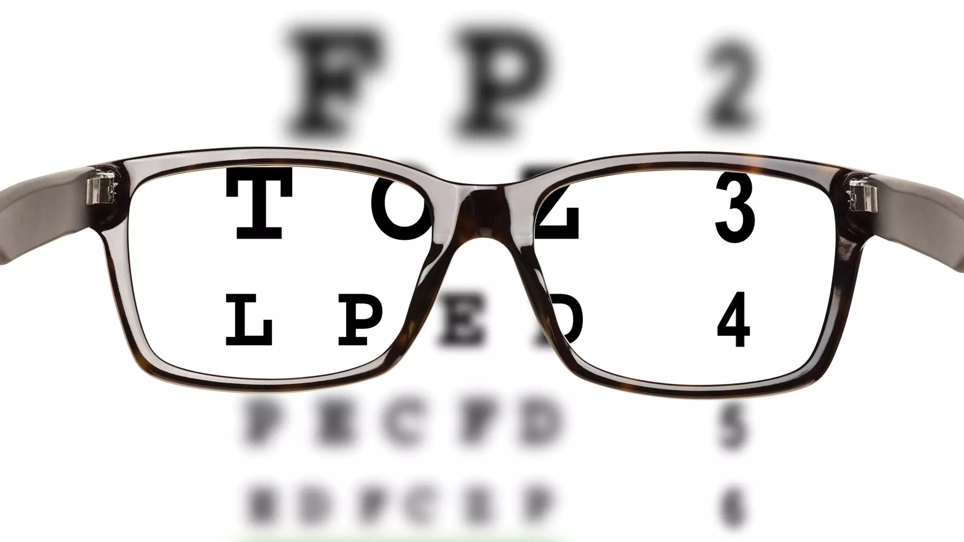Anteojos sostenidos frente a un gráfico que se usa para evaluar problemas de visión, que a menudo ocurren junto con el TDAH