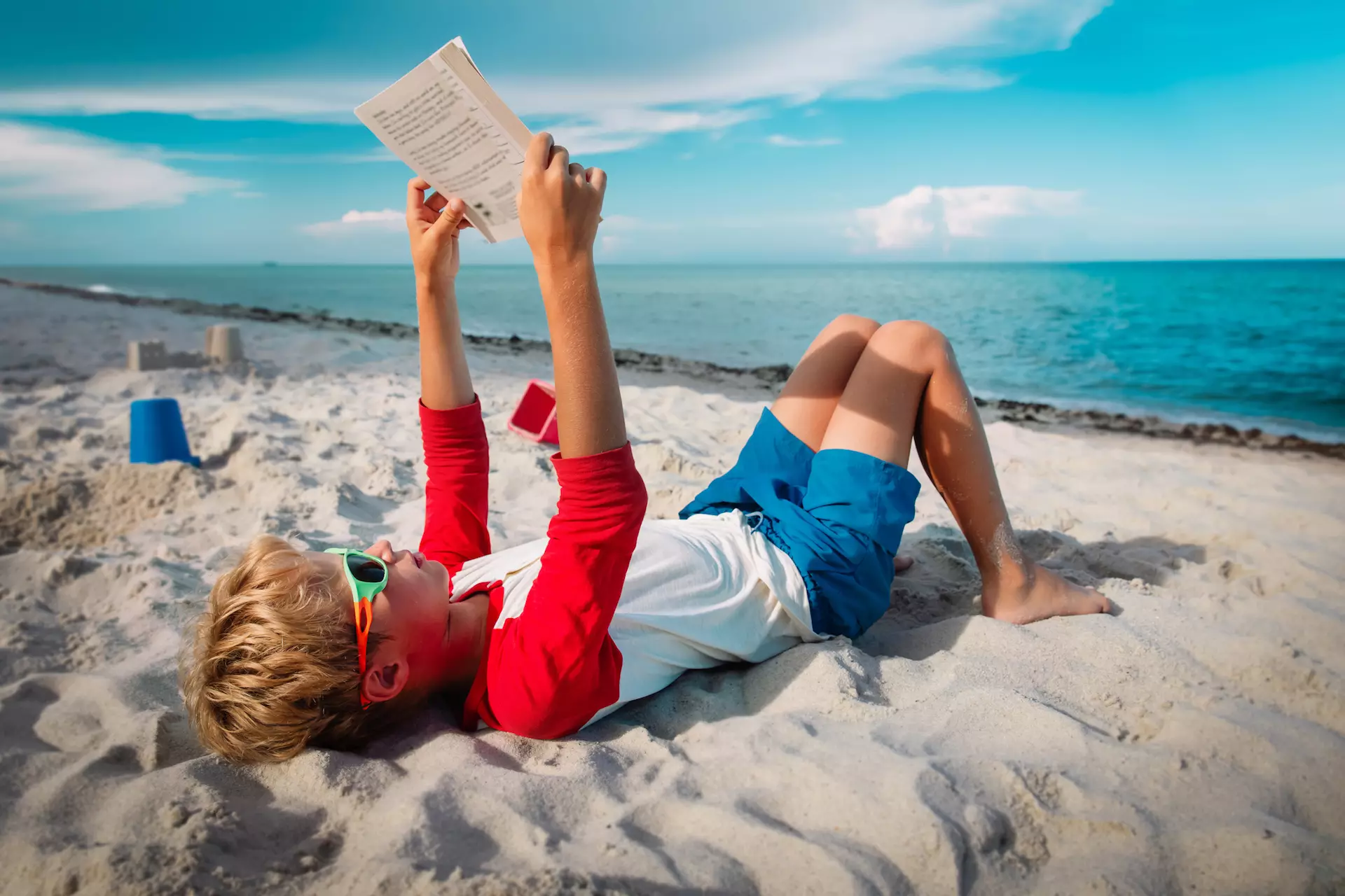मुलगा समुद्रकिनारी पुस्तक वाचत आहे