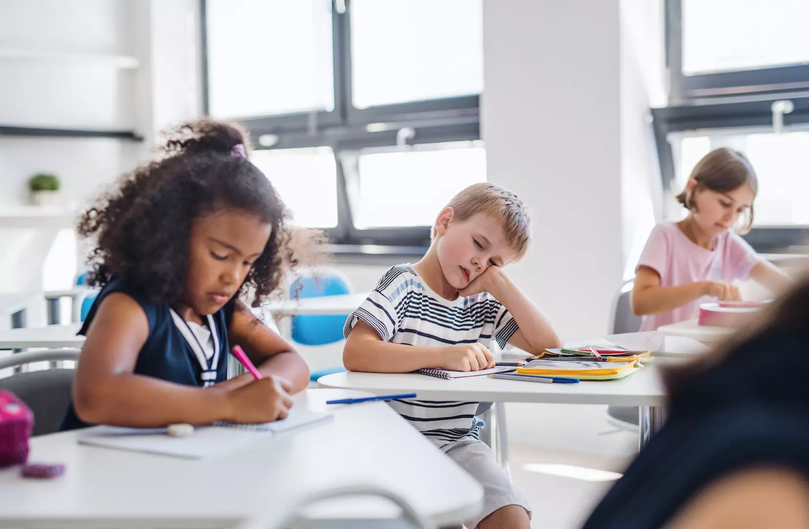 Малко уморено ученик седи на бюрото в класната стая и спи. Той може да се нуждае от функционална оценка на поведението и план за поведение.
