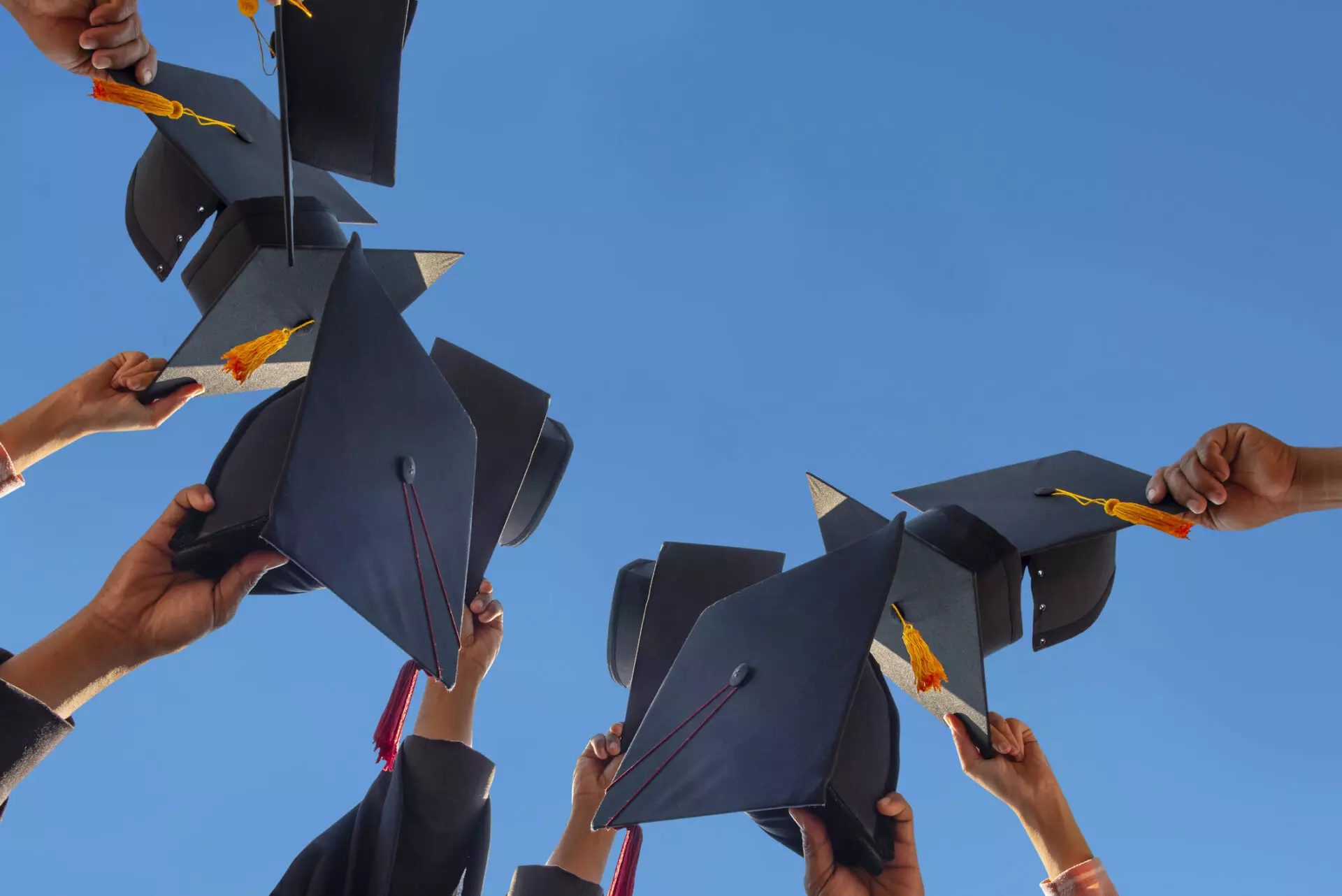 Els estudiants que sostenen un cop de la gorra de graduació amb la mà en un cel brillant durant la cerimònia es graduen amb èxit a la Universitat, Concepte d'educació amb èxit a Hight School, Grau felicitat