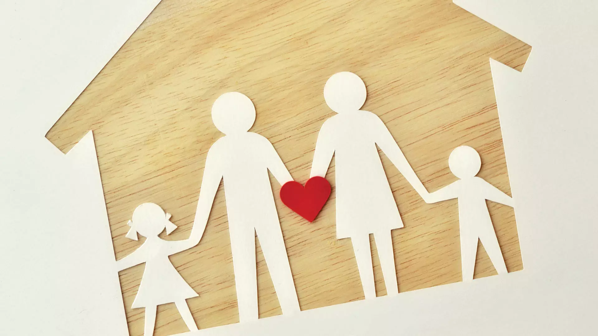 Eine Papierfamilie auf einem Holzhaus, die ein Herz hält, um Liebe, Unterstützung und ADHS-Hilfe darzustellen