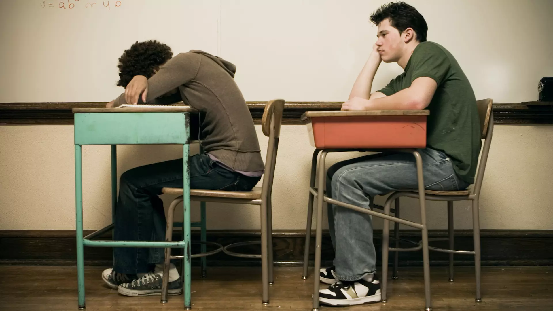 Dos estudiants asseguts als pupitres d'una aula