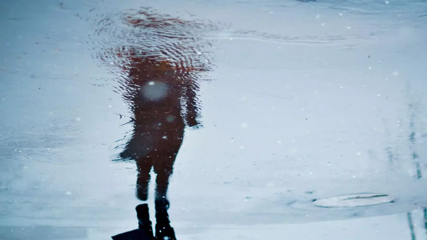 Per què sóc tan estrany? Imatge conceptual d'una dona reflectida a través d'un bassal en un dia fosc i plujós