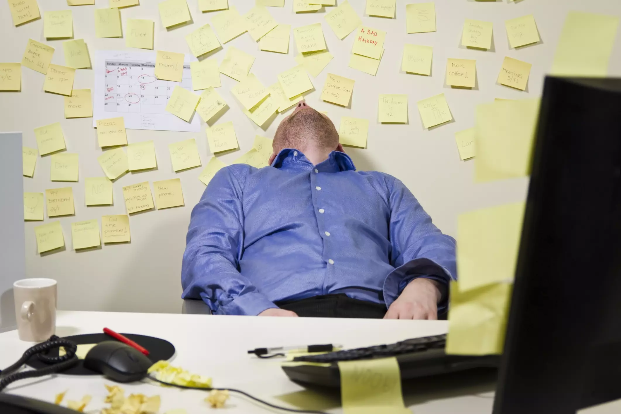 En træt mand på arbejdet kan ikke stoppe med at udsætte på grund af sin voksne ADHD.