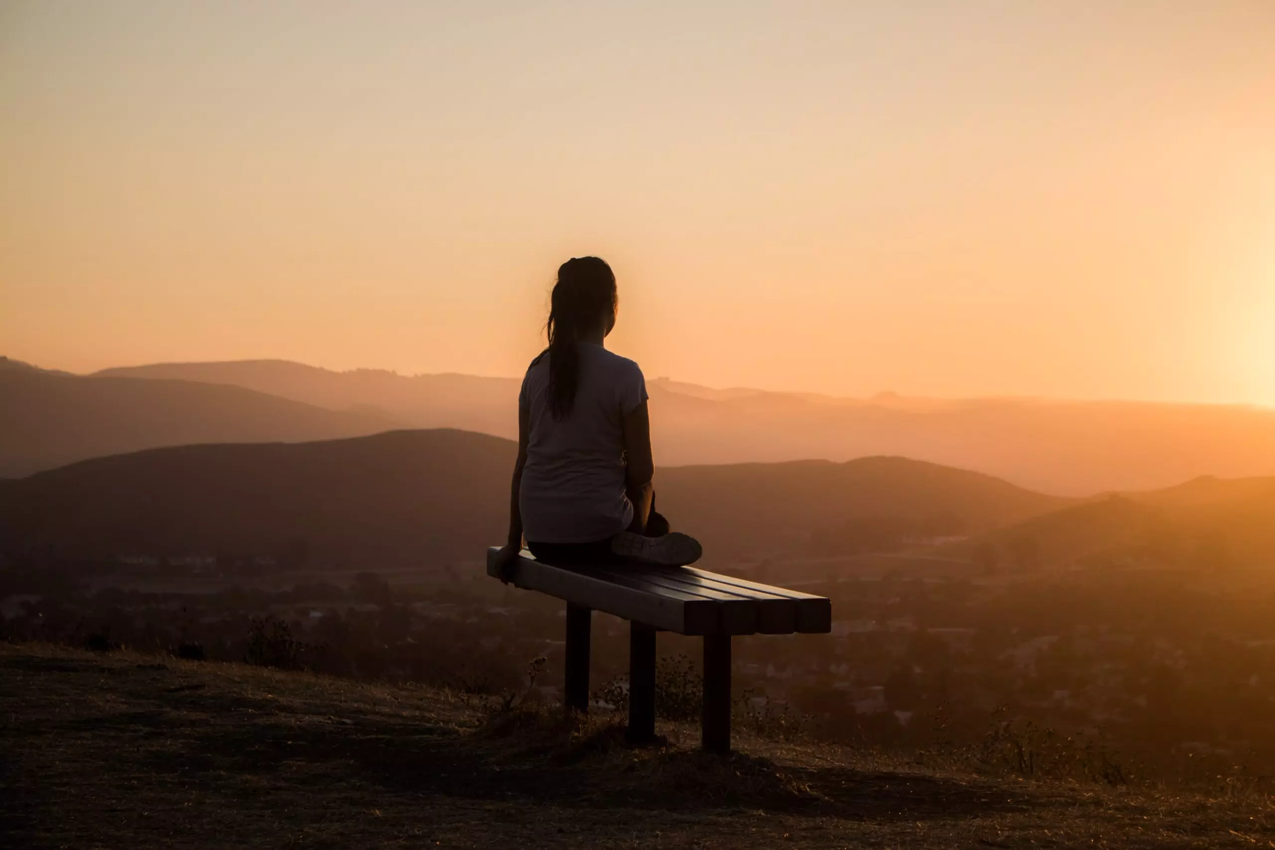 концепция самосострадания: женщина, сидящая на скамейке и смотрящая на горизонт