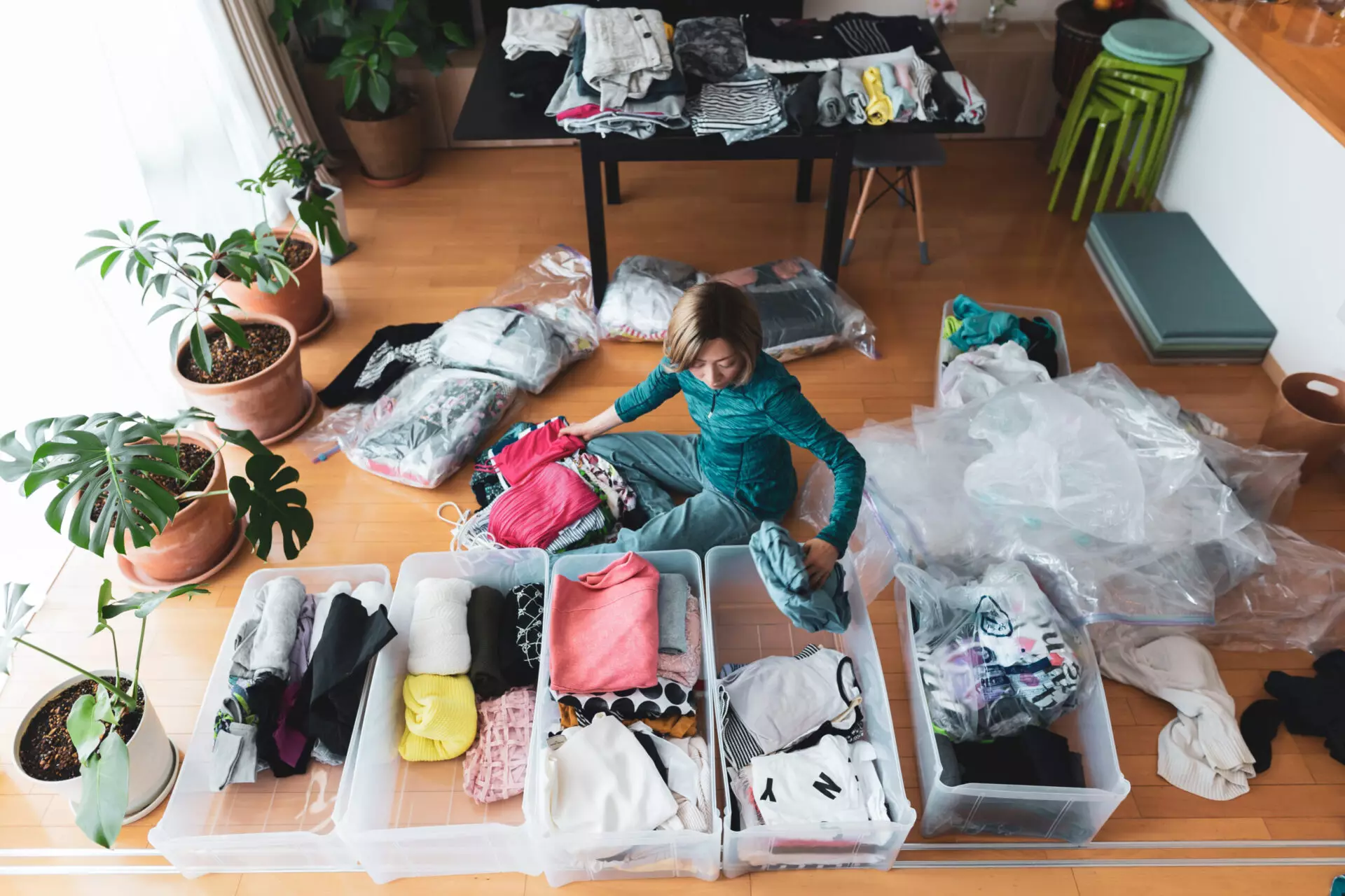 една жена организира облека во дневната соба од нејзиниот дом.