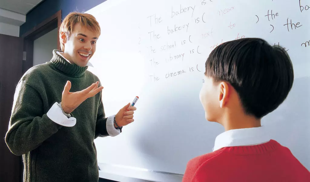 Учитель, работающий с учеником с СДВГ перед белой доской, с энтузиазмом объясняет планы уроков