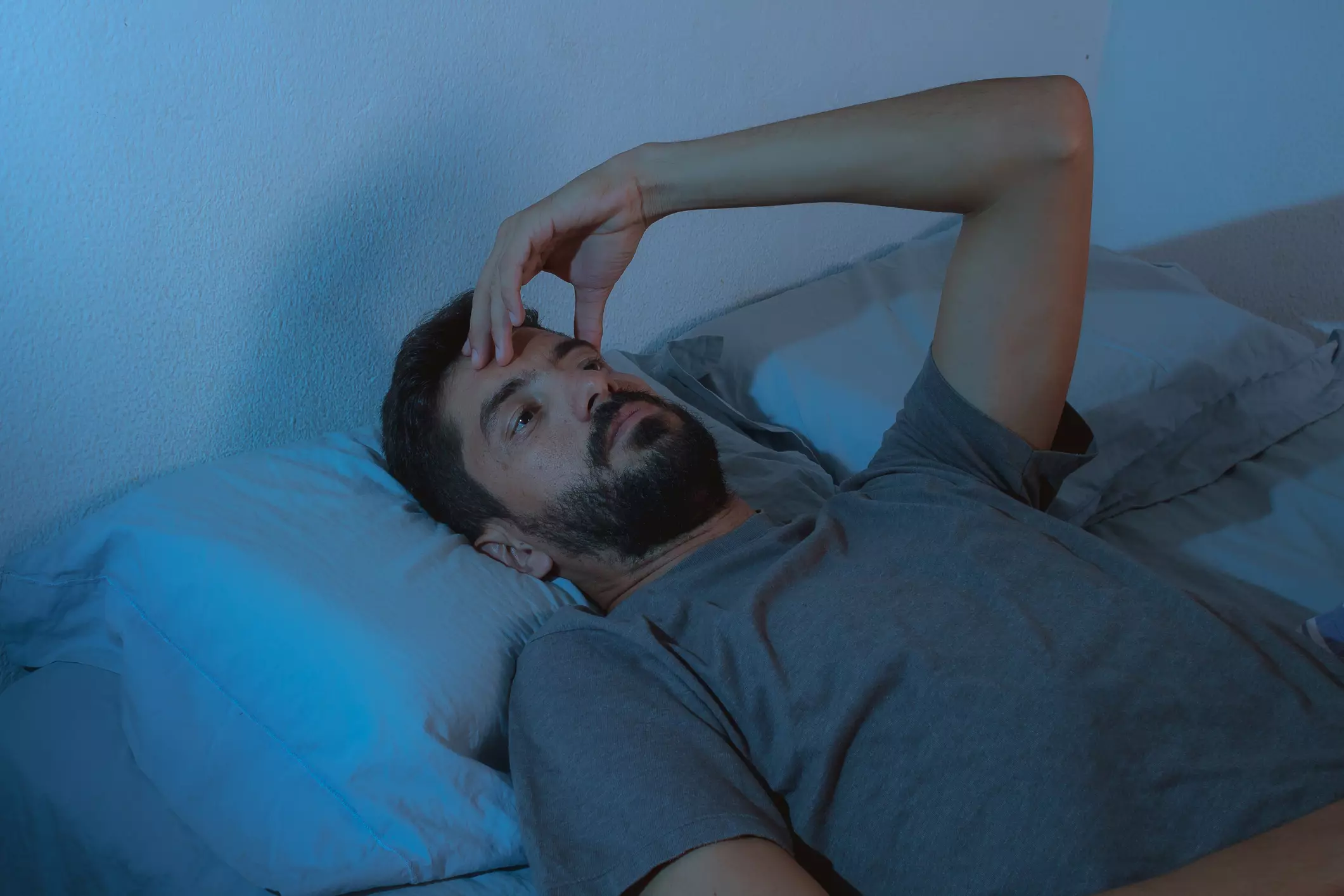 Seorang lelaki dengan ADHD berbaring di katil terjaga dengan insomnia