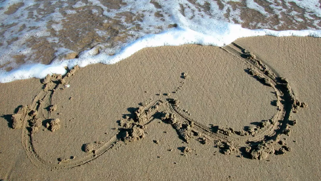 Corazón en la arena arrastrado por las olas, lo que representa problemas de relación de las personas con TDAH