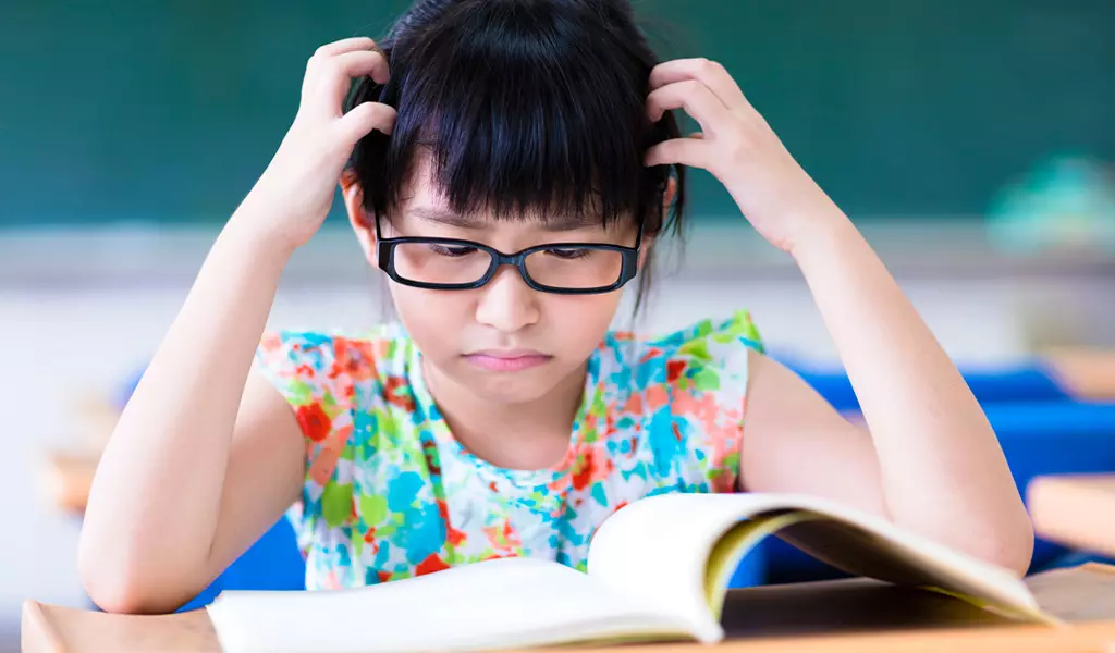 Dievča s ADHD vyzerá frustrovane a chytá sa za vlasy, keď sa snaží čítať