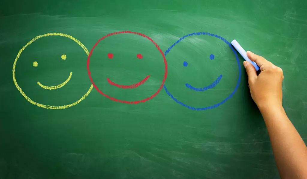 Три усмихнати лица, нарисувани на черна дъска в класната стая от ученик, участващ в кооперативно обучение