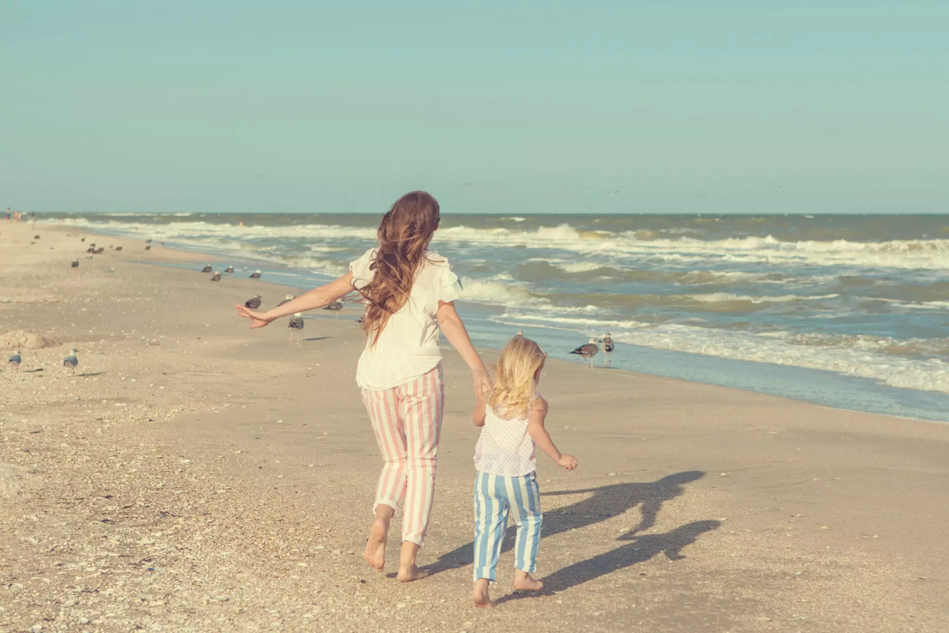 Laimīga ģimene. Jauna, skaista māte un viņas meita izklaidējas pludmalē. Pozitīvas cilvēka emocijas, jūtas.