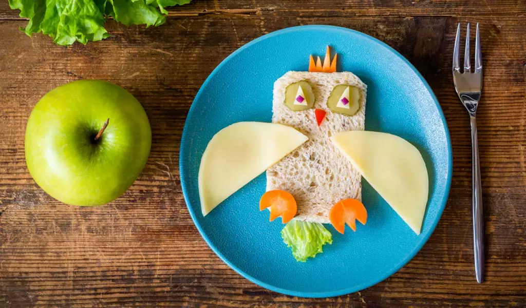 Pa, formatge, pastanagues, escabetx disposats com un ocell amb una poma al costat són un berenar saludable per als nens amb TDAH