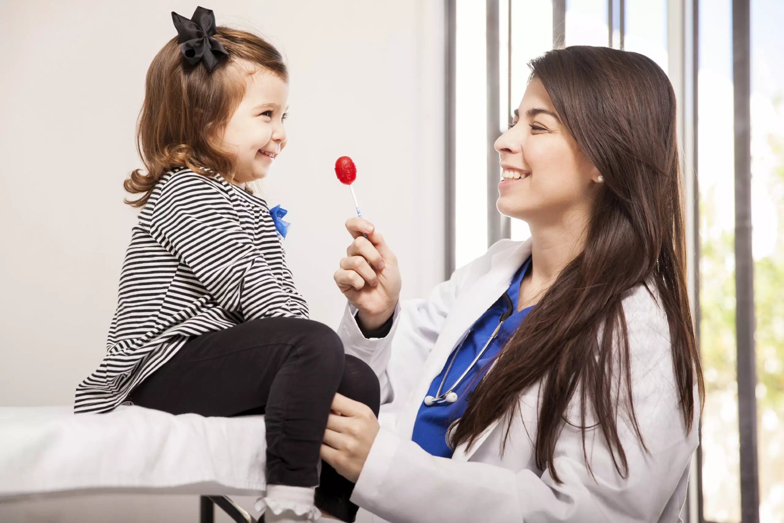 Pedijatrica daje lizalicu djevojčici u svojoj ordinaciji nakon procjene Touretteovog sindroma i dijeljenja osnovnih činjenica.