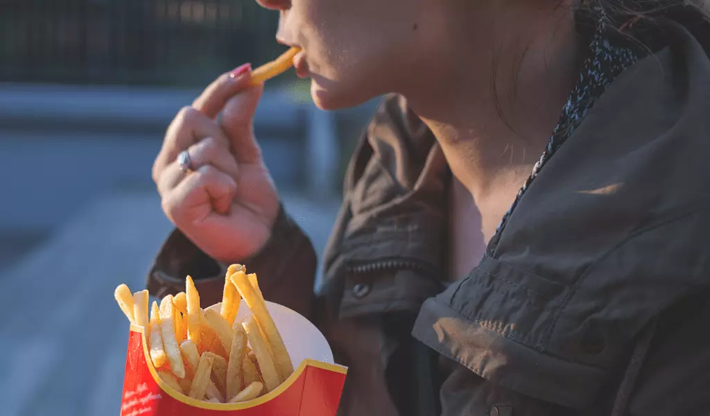 En kvinna med ADHD som impulsivt äter pommes frites