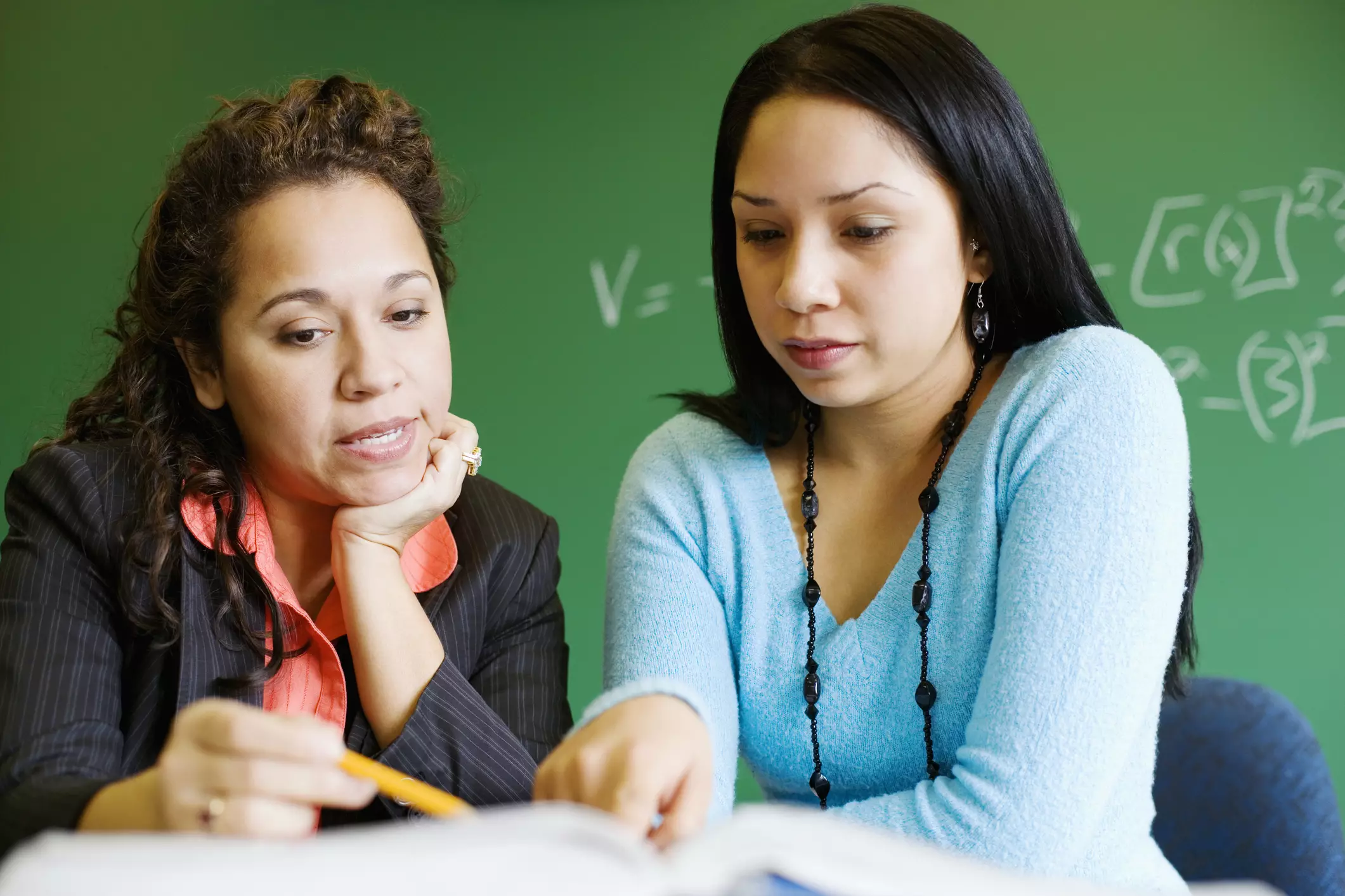 Un dúo de maestros y padres revisan juntos un IEP, algo clave que se debe hacer antes de que comiencen las clases.