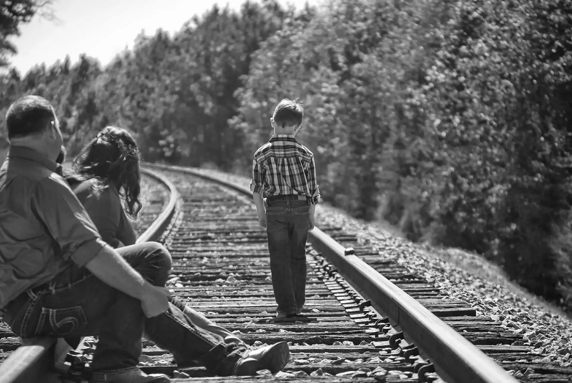 Семья смотрит, как сын с СДВГ идет по железнодорожным путям
