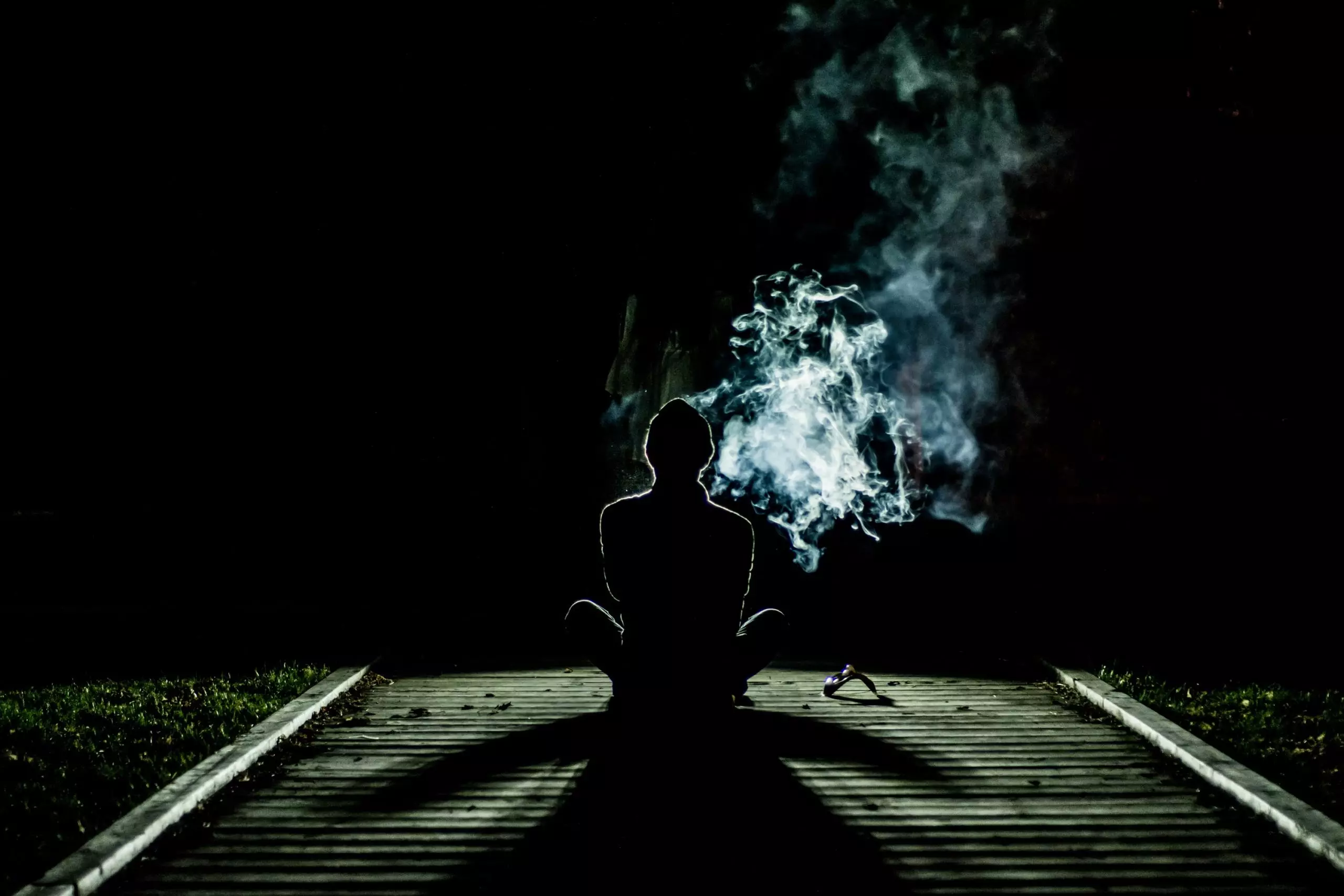 Un adolescente sentado na pista, fumando