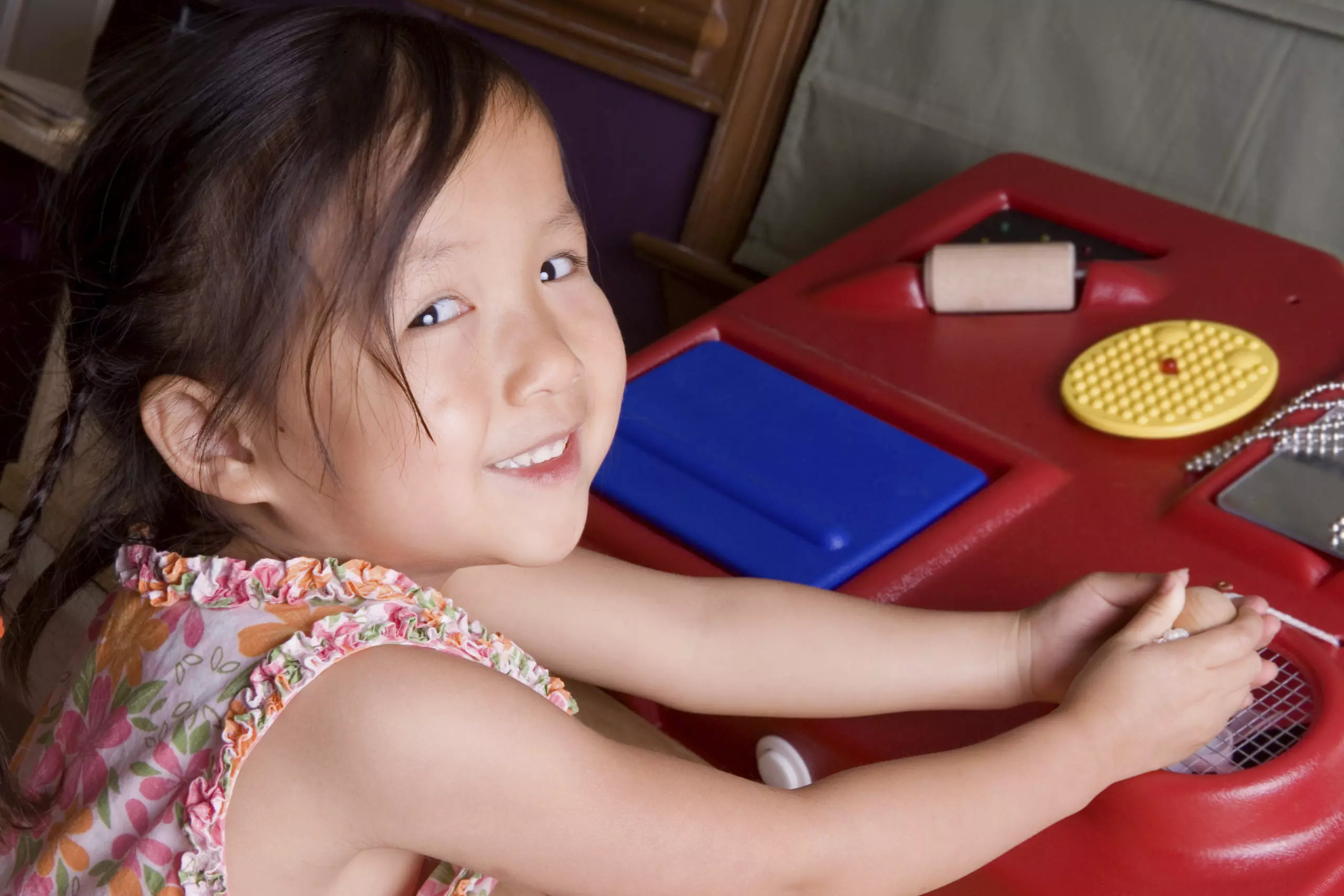 Unha nena con SPD xoga cunha mesa sensorial.