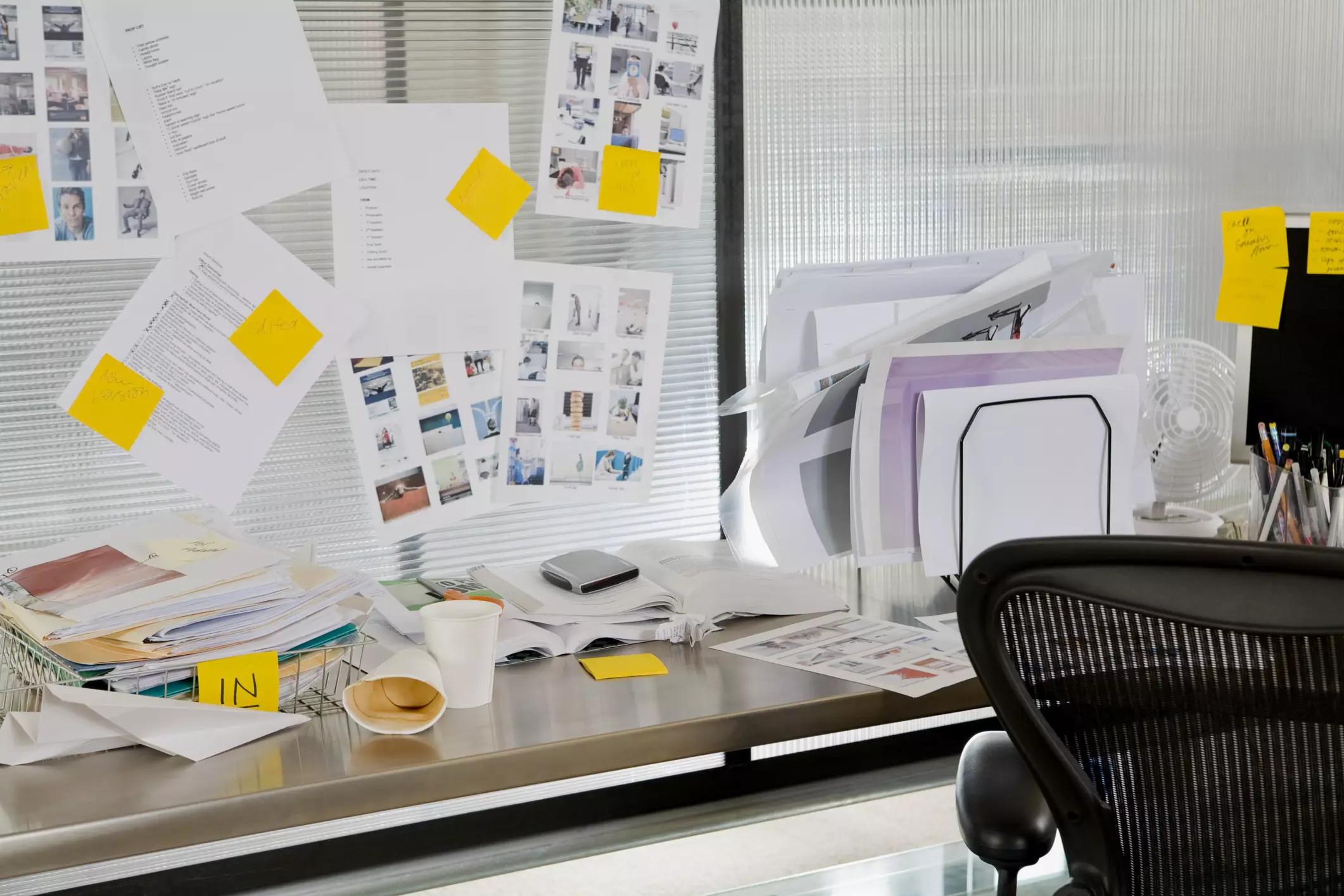 Разхвърляно бюро на възрастен с ADHD с хартии, лепенки и чаши