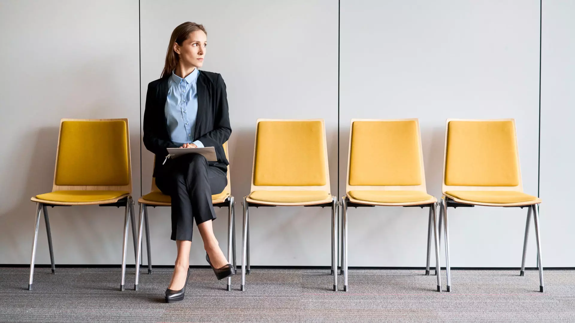 Ung kvinde sidder i lobbyen med CV i hænderne og venter på jobsamtale