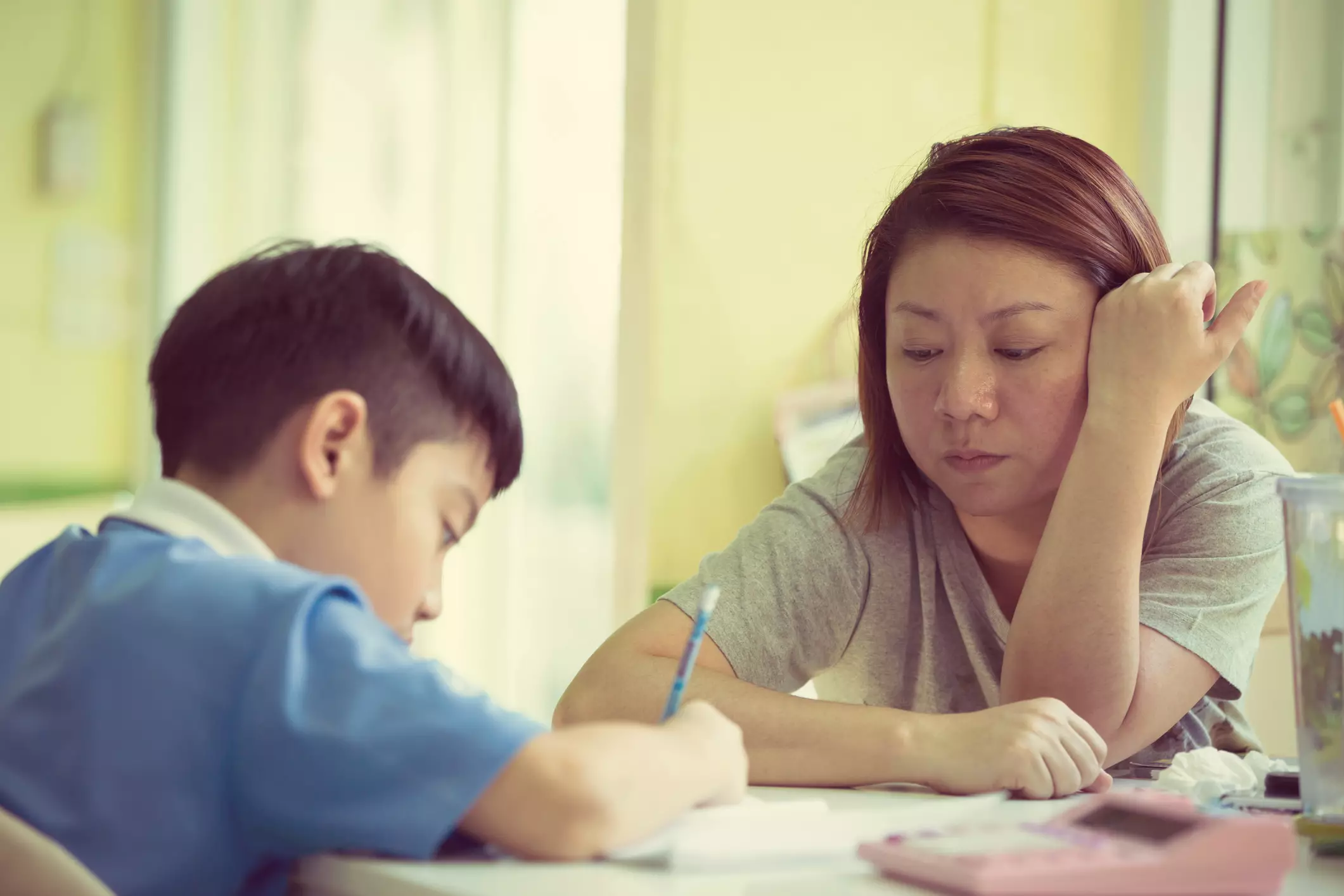 妈妈帮助男孩做作业，以帮助解决执行功能障碍。