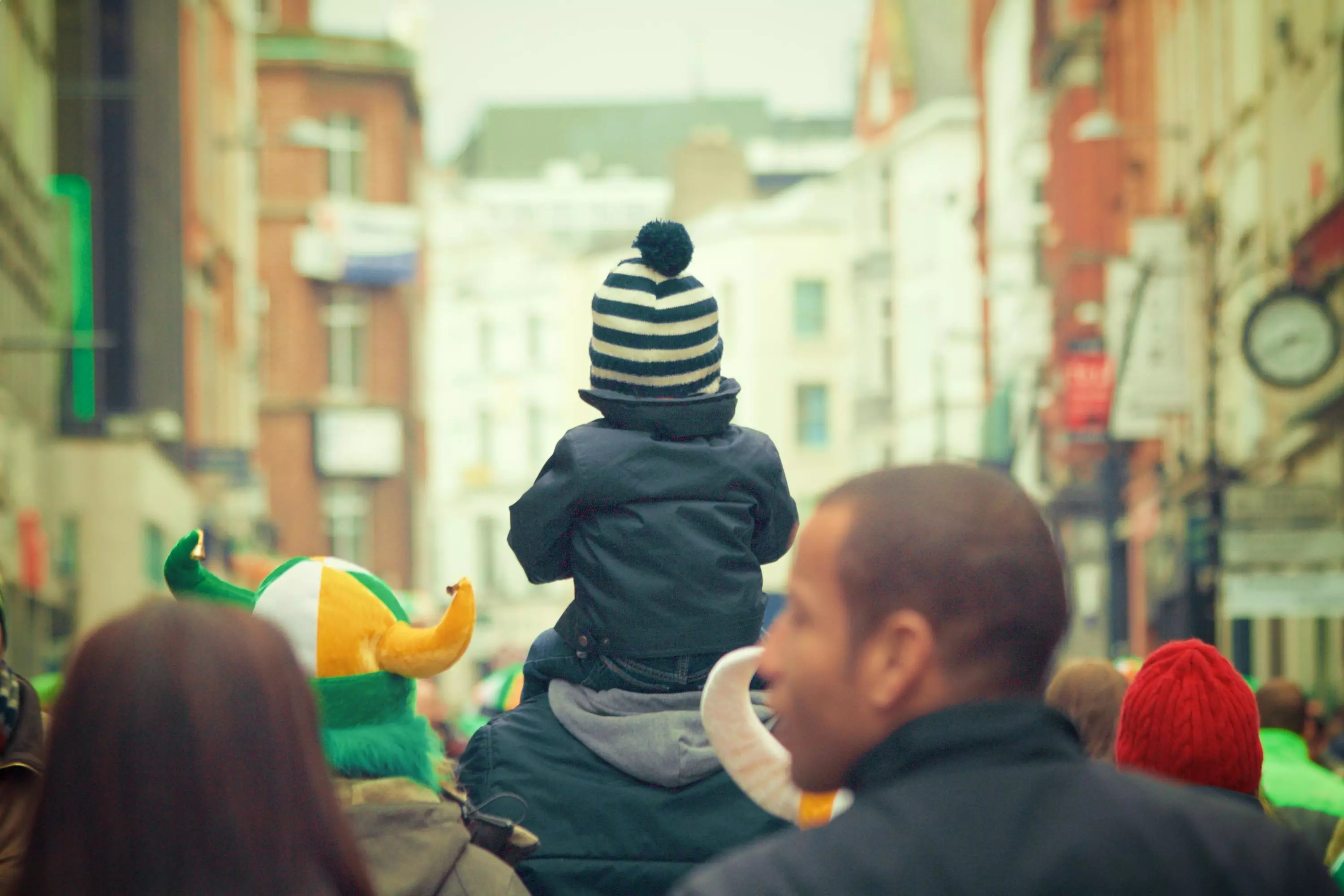 Толпа луѓе кои шетаат и со дете со АДХД на рамото на човекот