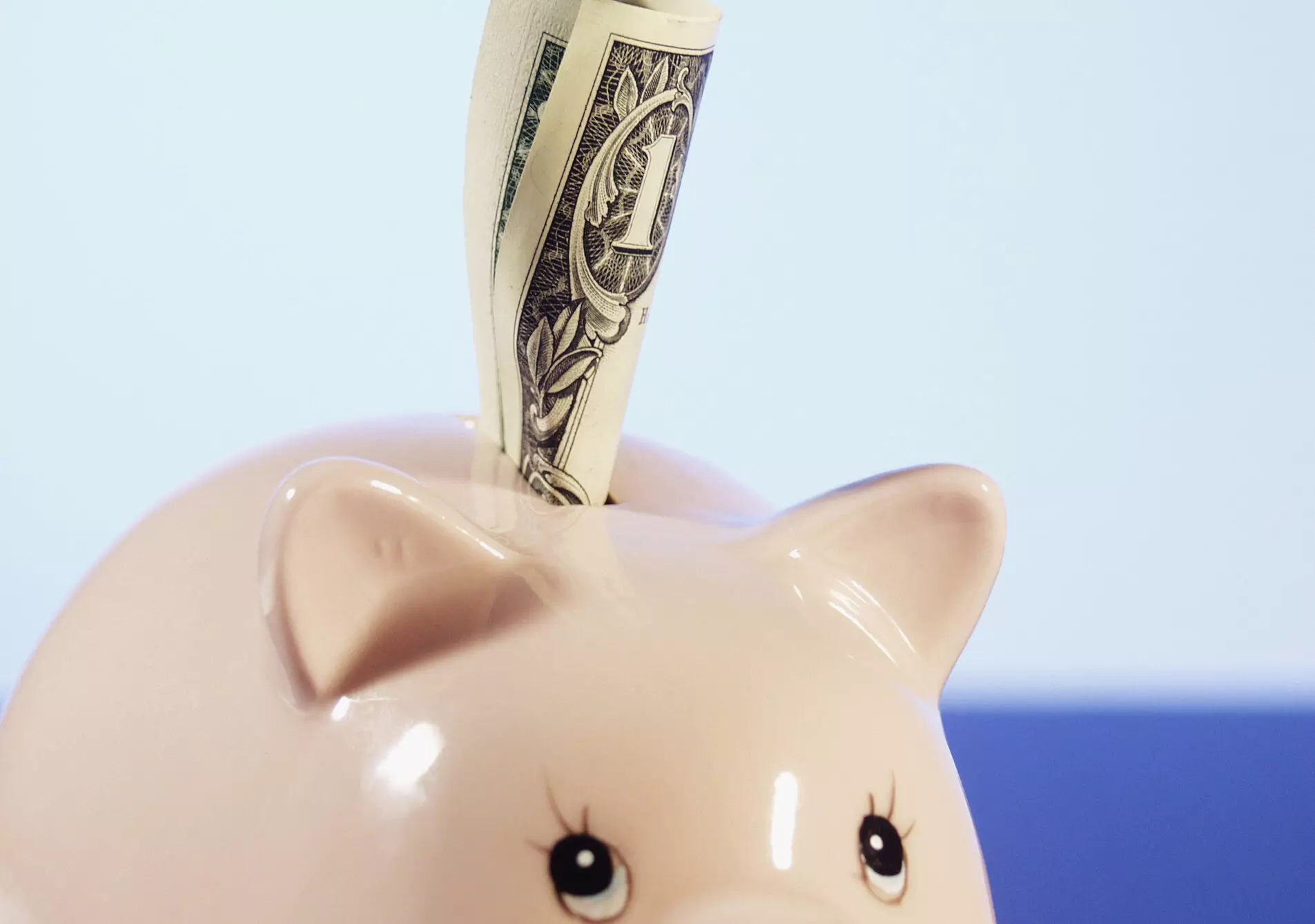 Ein Dollar, der aus einem Sparschwein ragt, eine Erinnerung daran, nicht mehr zu viel Geld auszugeben.
