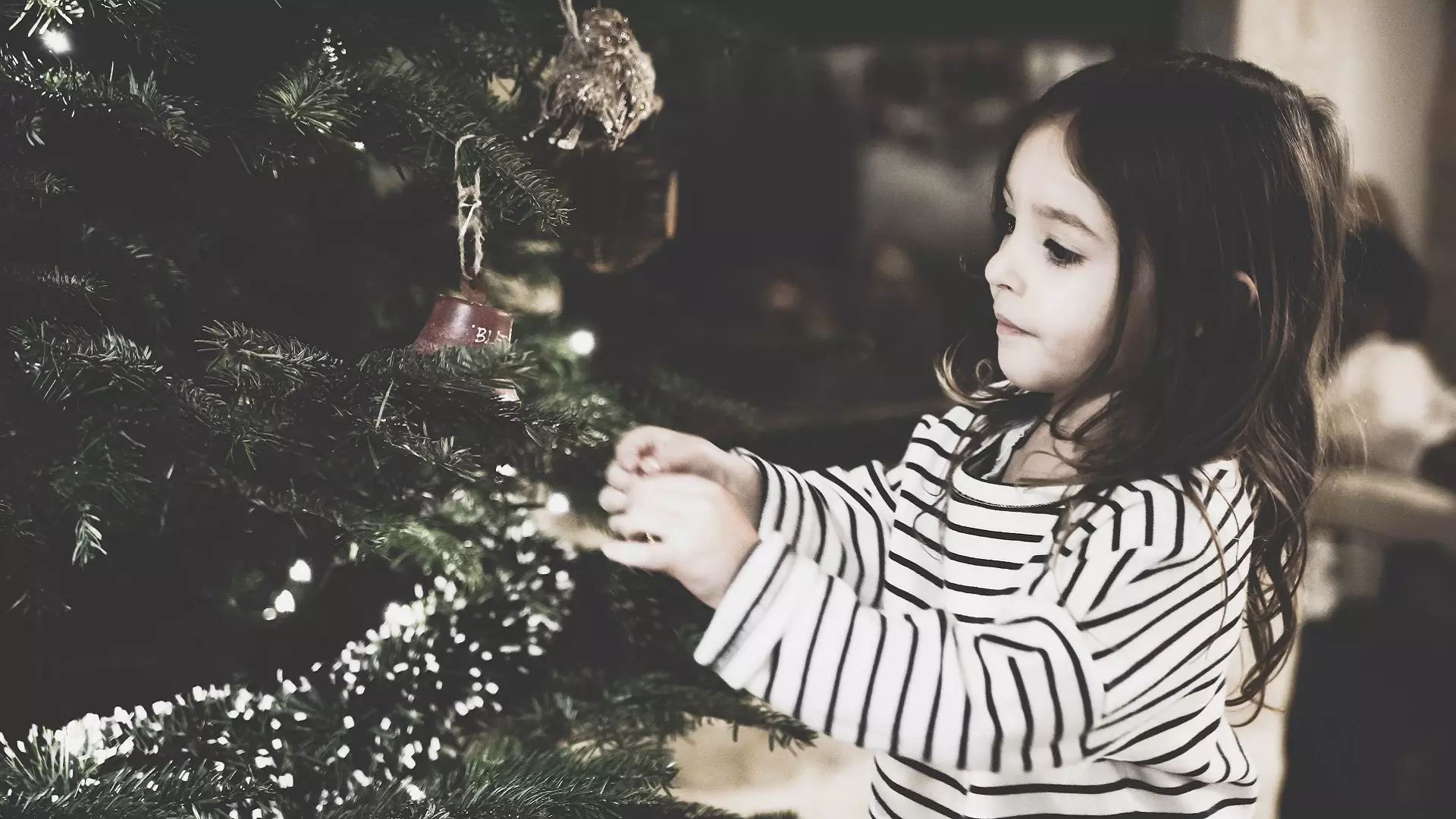 Una niña con TDAH decora un árbol, minimizando el estrés de las fiestas con buen comportamiento