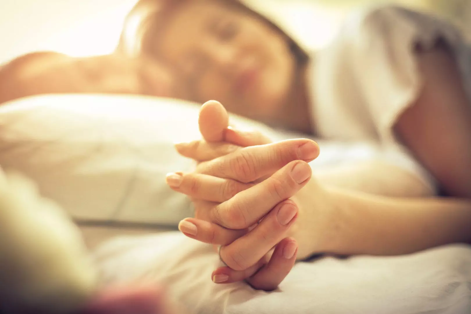 זוג הטרוסקסואל מחזיק ידיים במיטה. המפתח לזוגיות טובה יותר? סקס טוב יותר, על פי סקר זוגות חדש של ADHD.