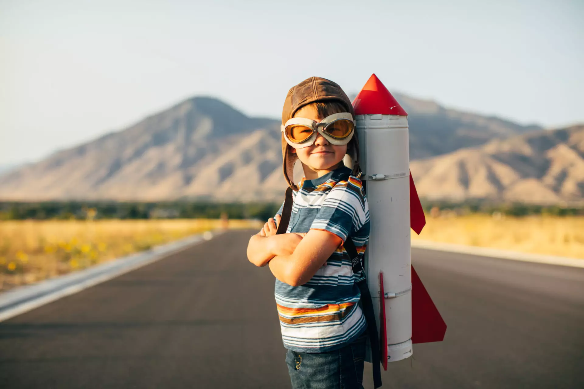 Младо момче кое носи летечки очила има ракета врзана на грбот додека е подготвен да лета на нови имагинарни места. Слика направена во Јута, САД.