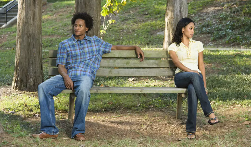 ชายและหญิงที่มีสมาธิสั้นนั่งอยู่บนม้านั่งทั้งสองข้างในสวนสาธารณะ