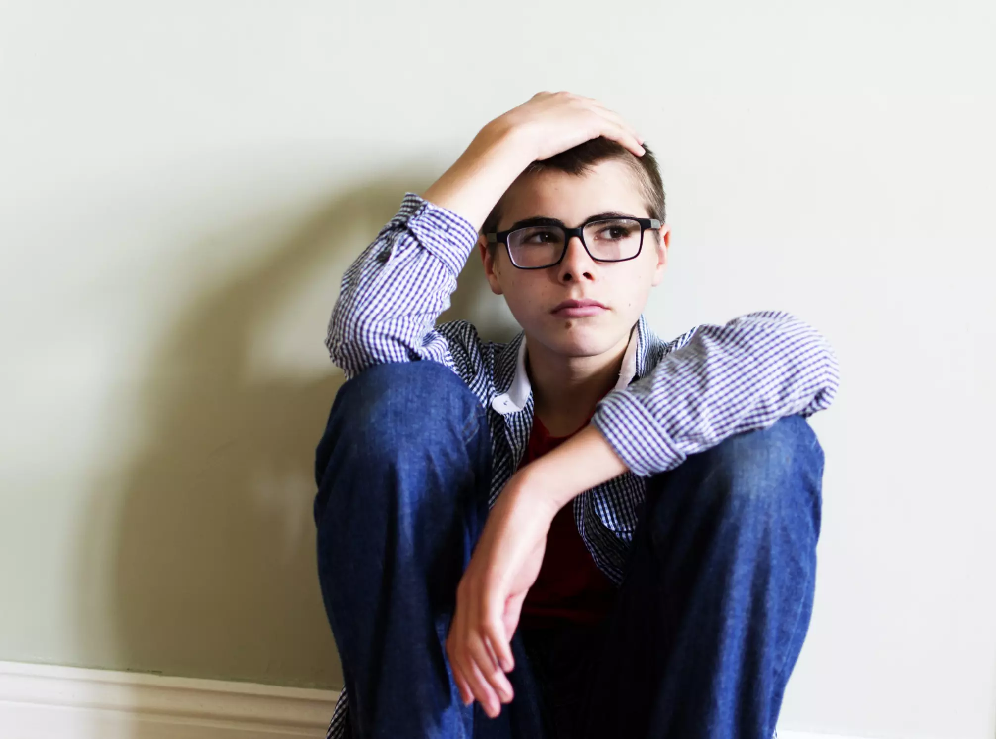Djali adoleshent me ADHD ulet në dysheme për mur i frustruar nga nevoja për të marrë mjekim