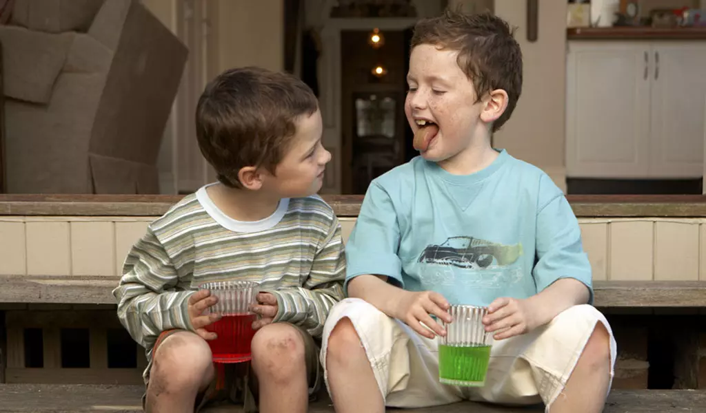 TDAH duten bi mutil kanpoaldeko eskaileretan eserita soda koloretsua edaten eta mihia ateratzen.