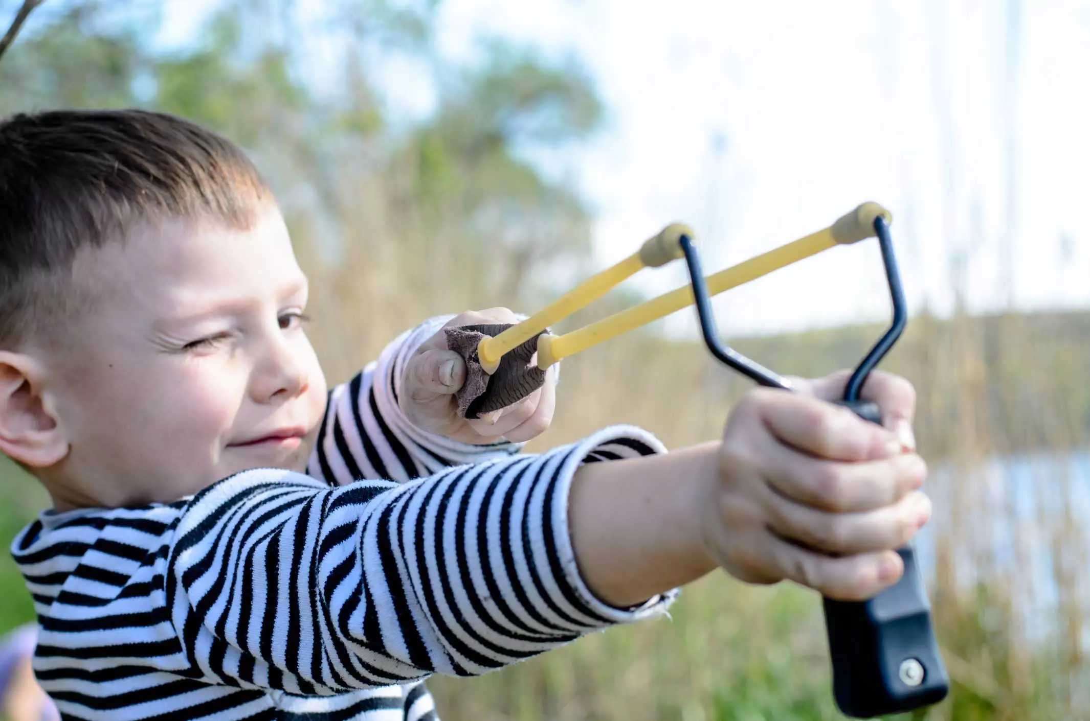 Một đứa trẻ vui vẻ khi chơi với súng cao su, đã cải thiện các triệu chứng ADHD thông qua liệu pháp tương tác giữa cha mẹ và con cái
