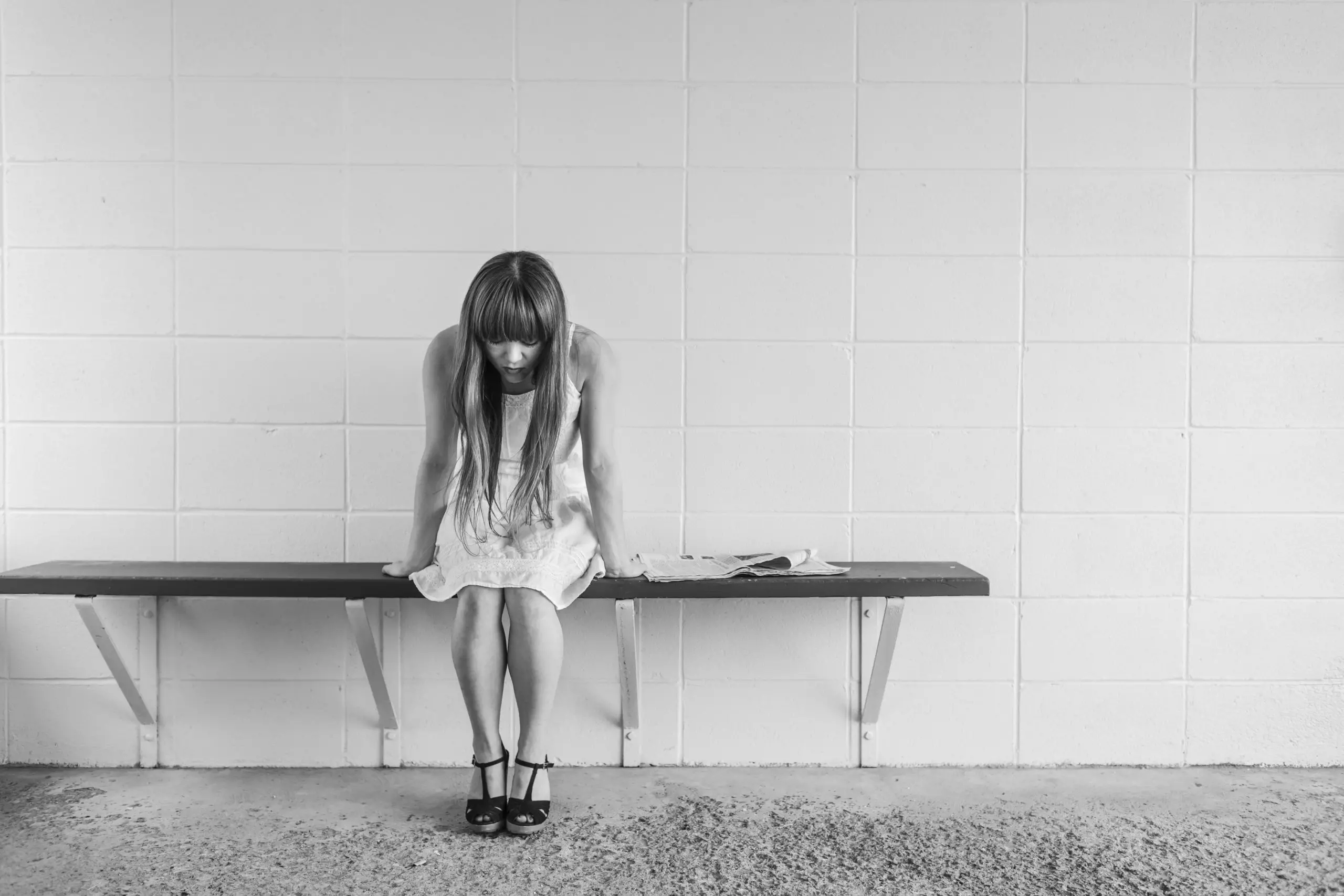 Жінка з ознаками аутизму у дорослих сидить сама на лавці, почуваючись емоційно, бо хвилюється