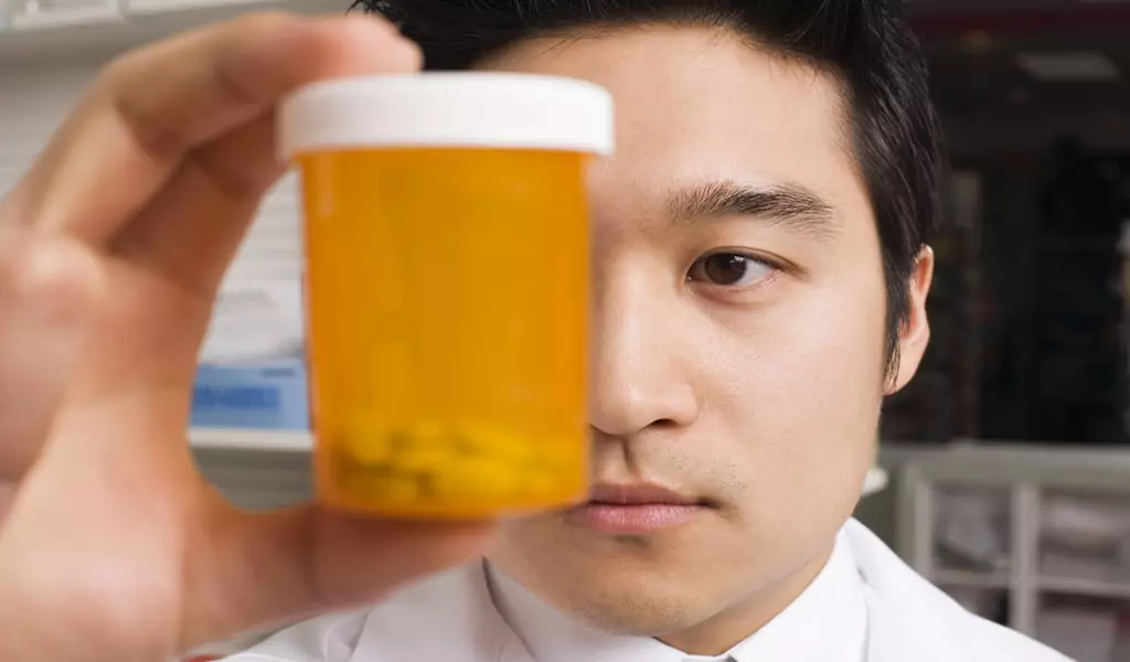 Дозировка на Adderall: Доктор, който държи бутилка с хапчета в лице с лекарството за ADHD в нея