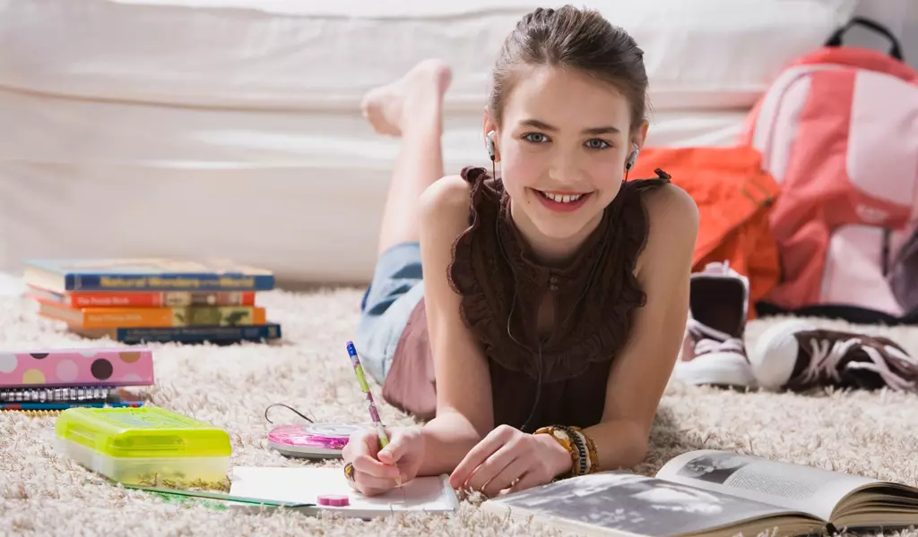 Дівчина з СДУГ робить домашнє завдання на килимі з книгами.