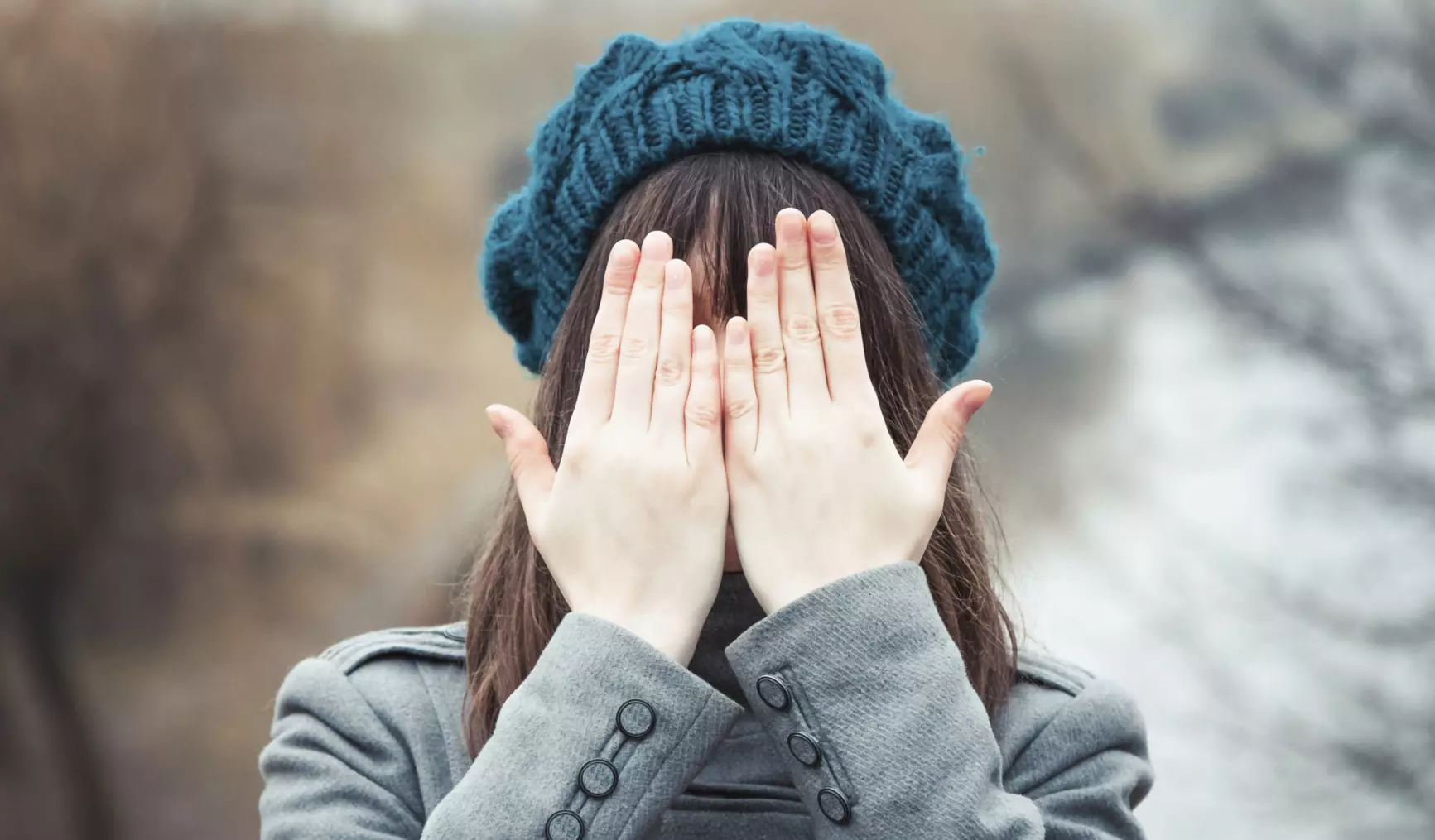 Jente med ADHD dekker ansiktet med hendene utenfor