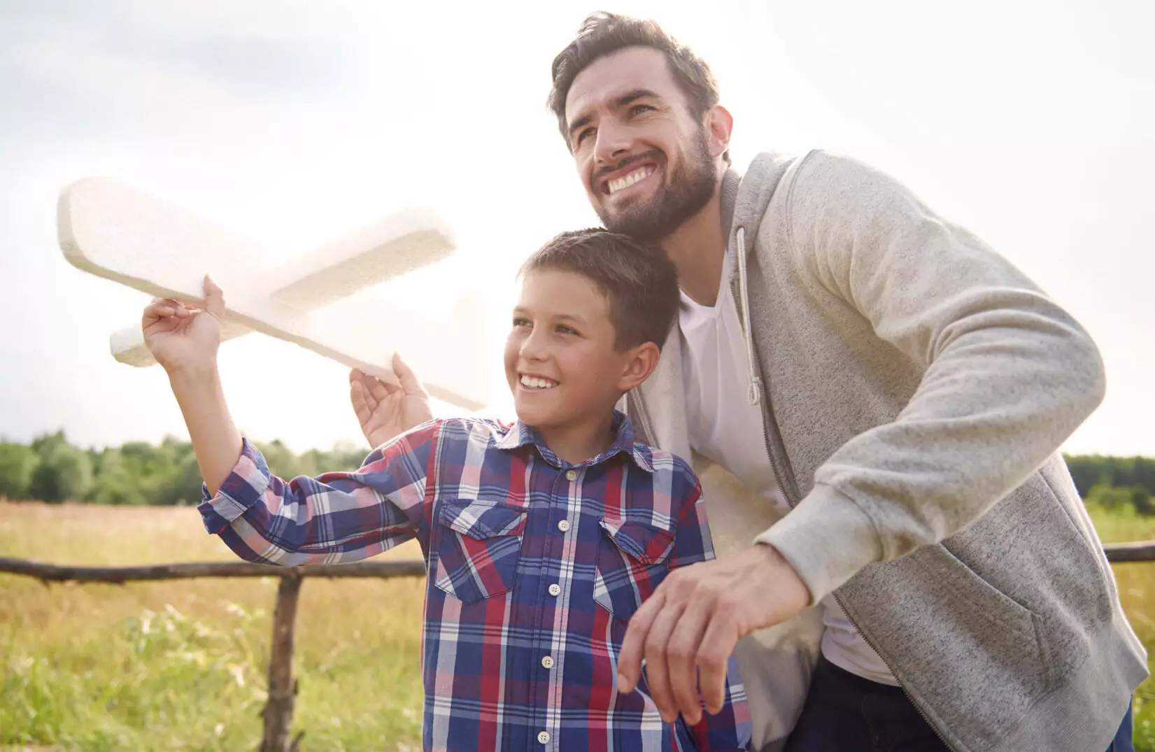 Vater und Sohn mit ADHS fliegen Papierflieger draußen auf dem Feld