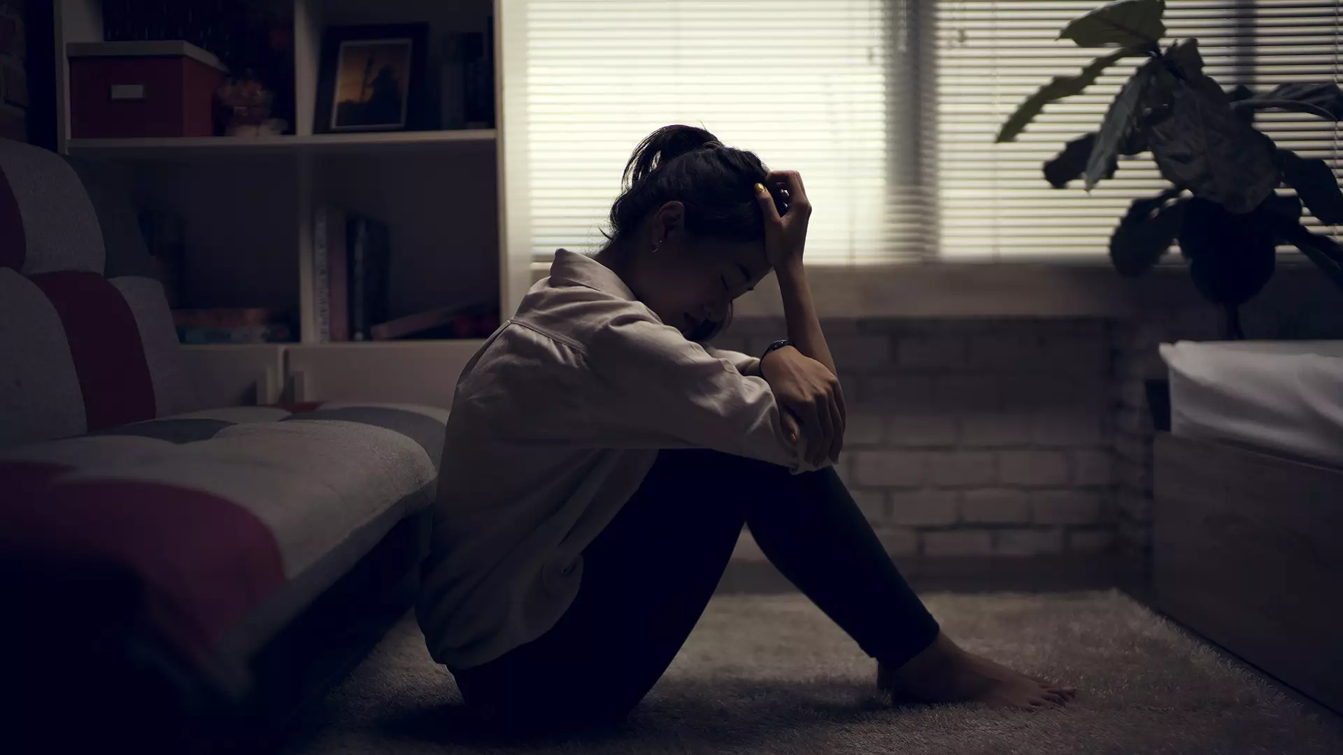 Una mujer con depresión se sienta en una habitación a oscuras.