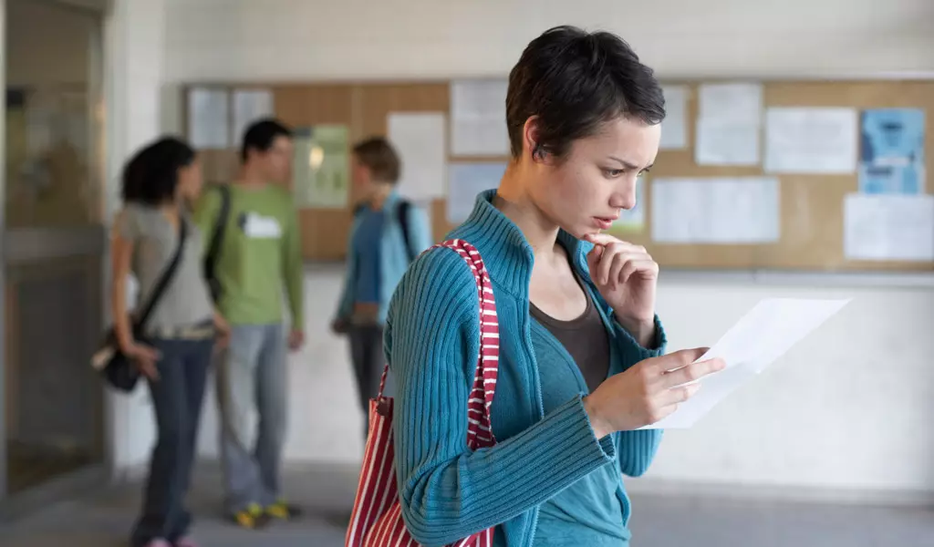 Teenager med ADHD ser på papir i gymnasiets gang