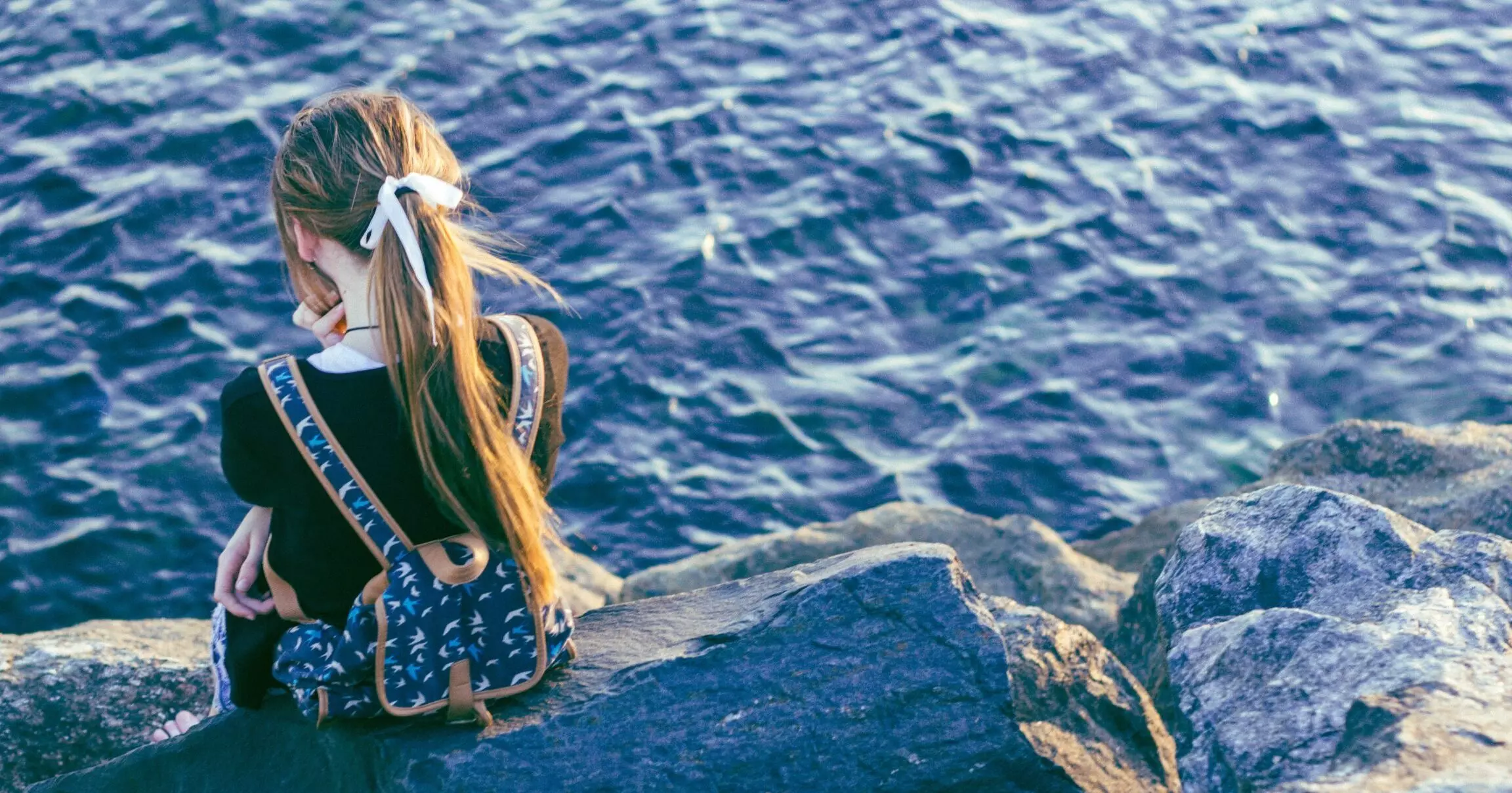 Petite fille face à la caméra et regardant vers l'eau, symbolisant le TDAH et le retrait émotionnel chez les femmes